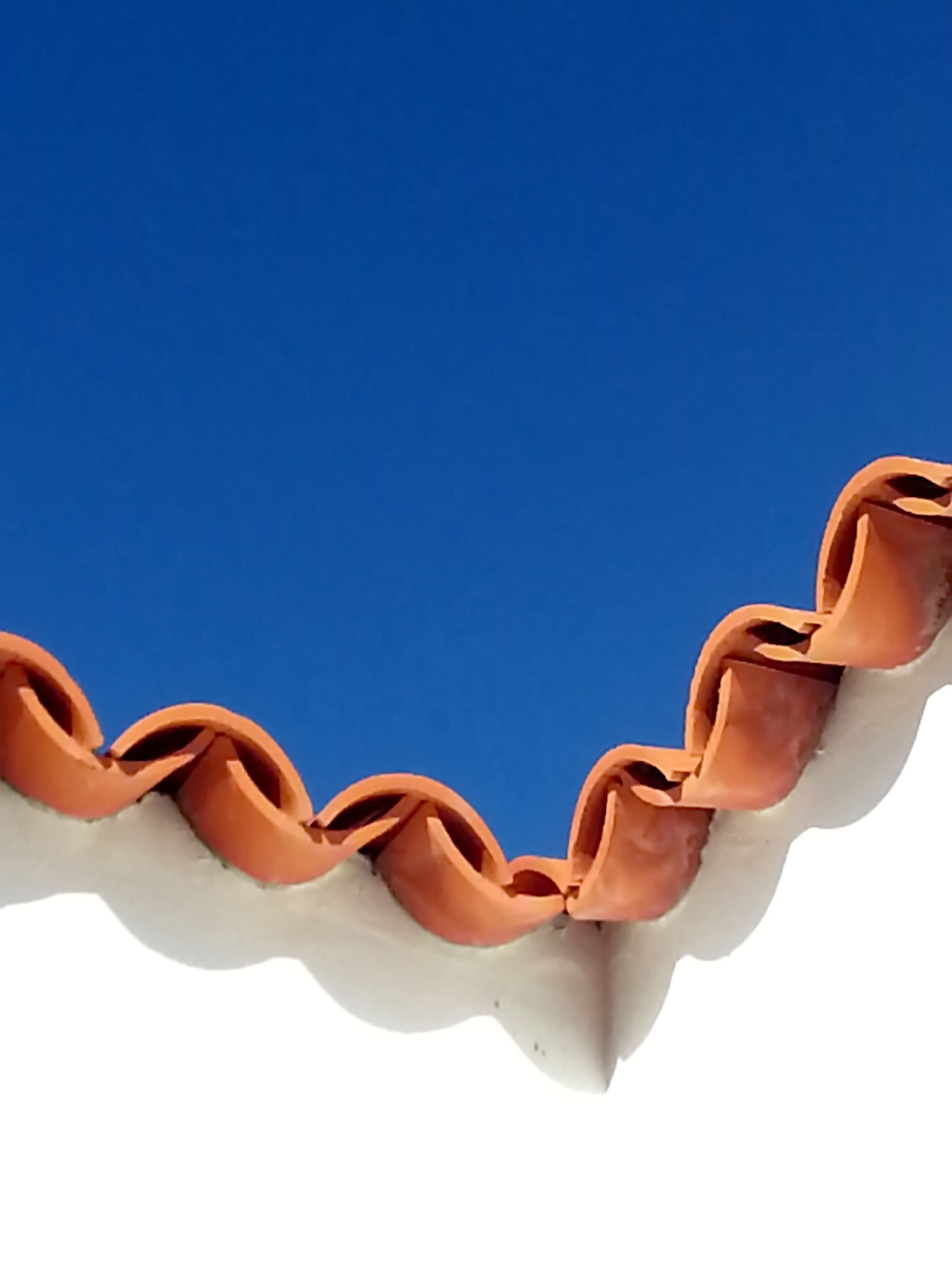 Brick roof panels against a bright blue sky free image download
