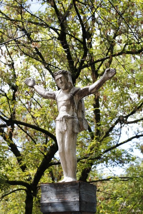 Beautiful sculpture of Jesus near the green trees free image download