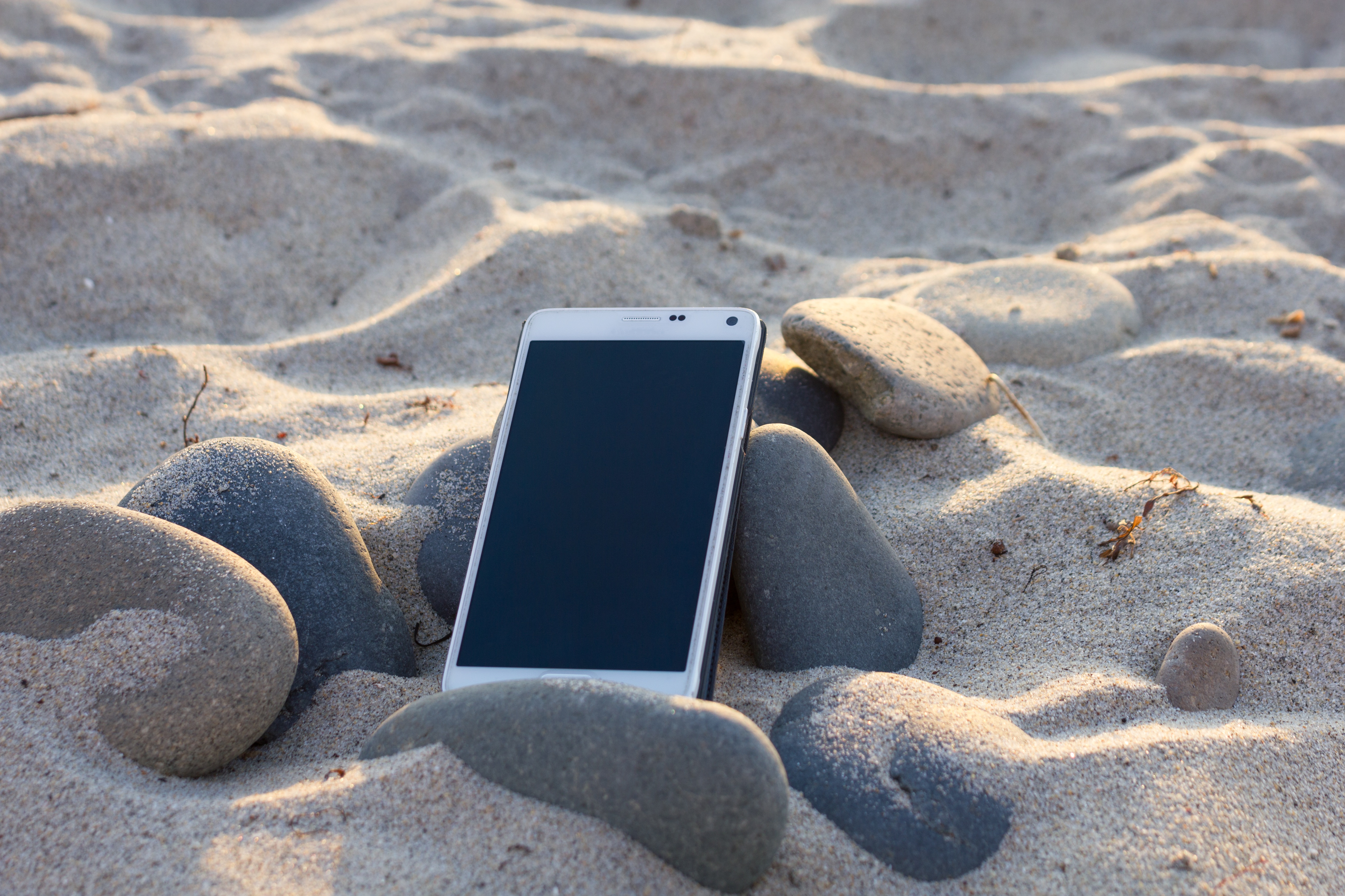 Cell phone on the stones in the sand free image download