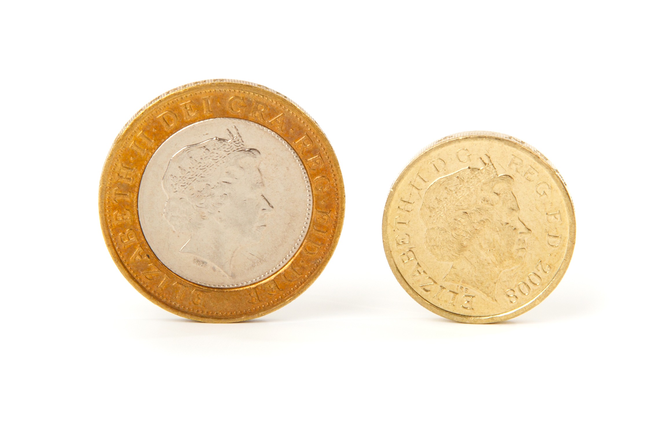 Shiny, colorful, metal British coins with shadows, on white surface ...