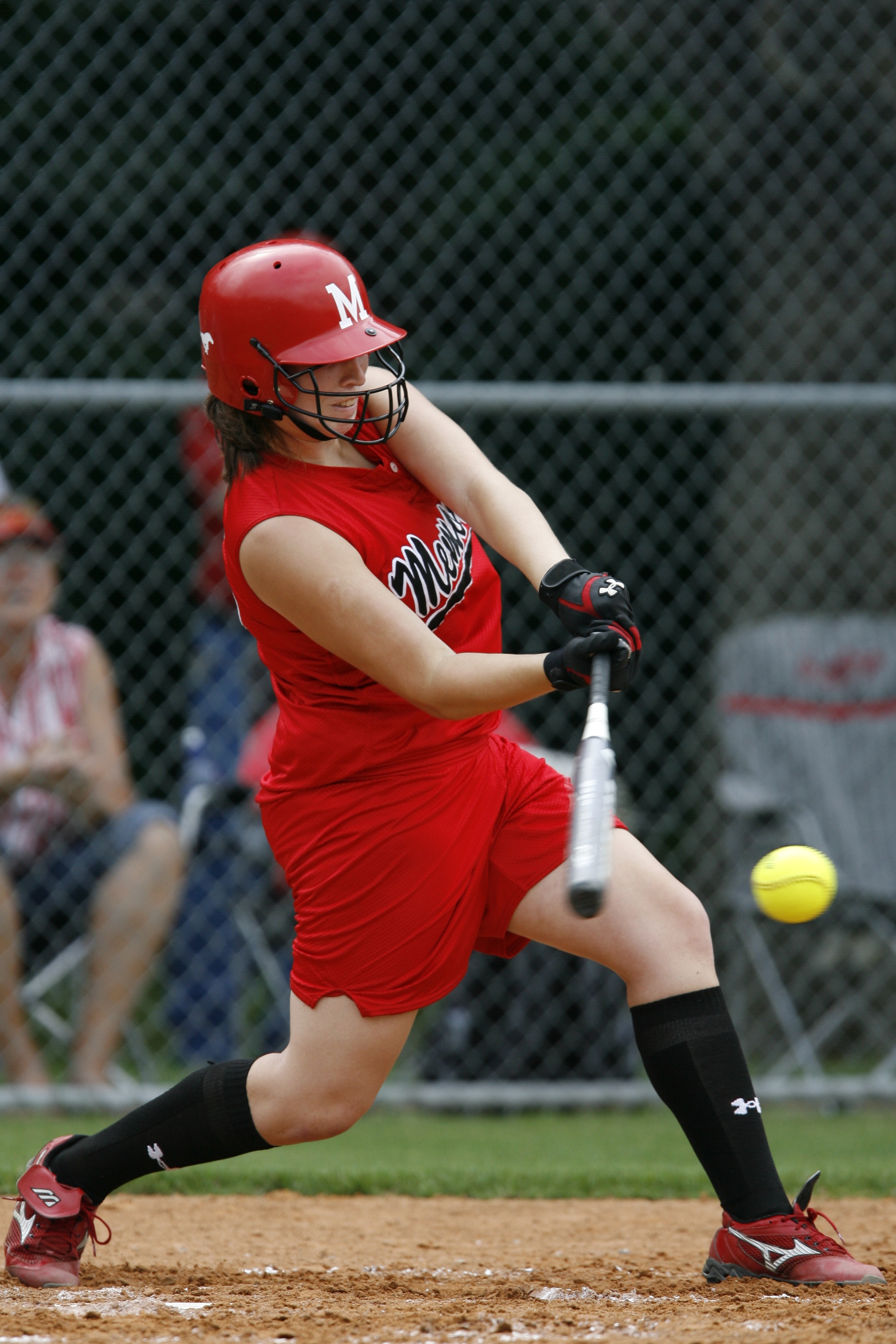 Softball girl player with the bat, and ball, on the field with fence ...