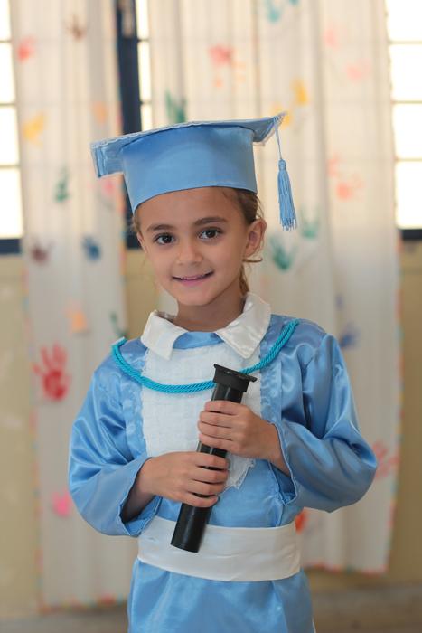 Smiling boy in turquoise and white clothing, on the school graduation ...