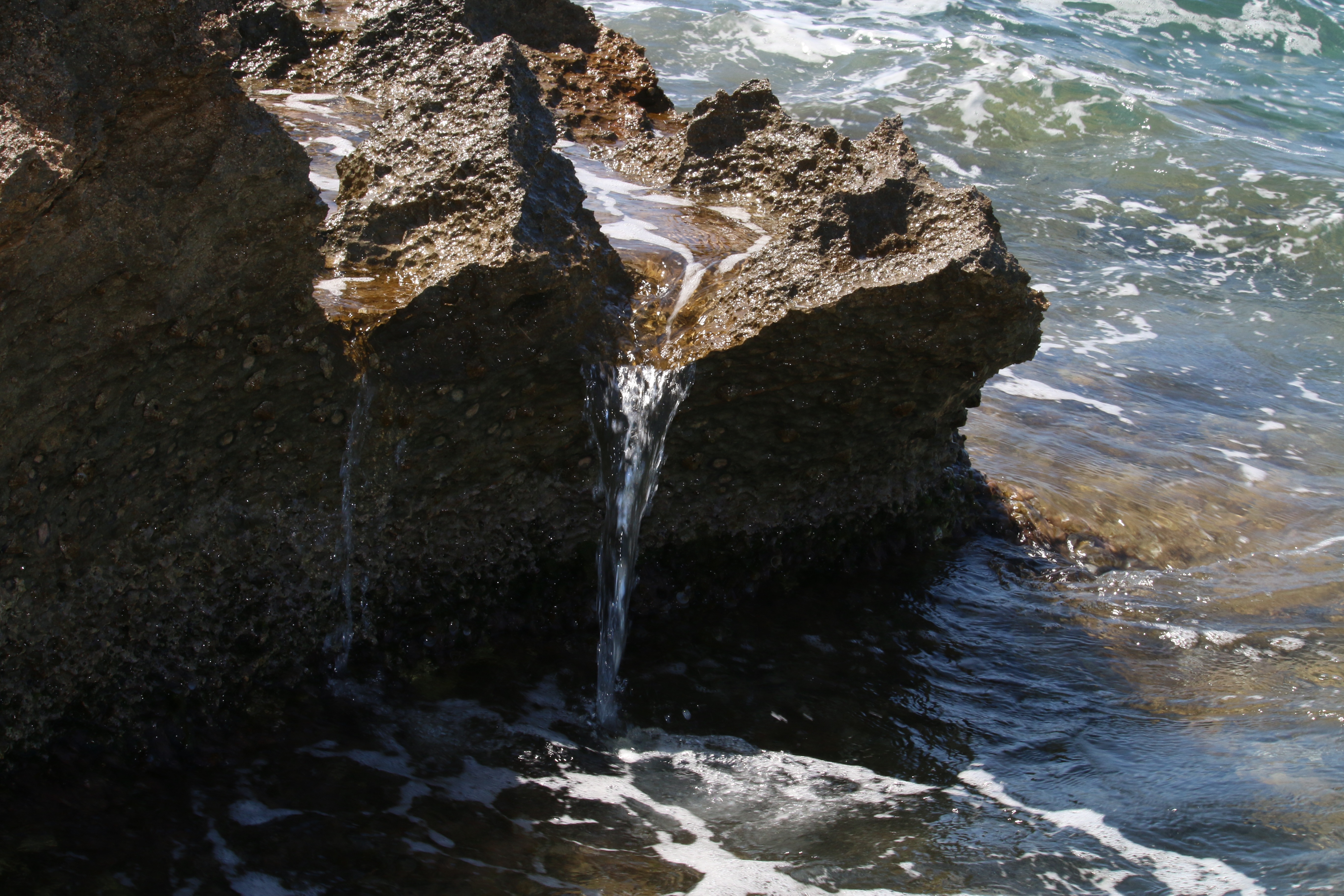 Water flows down the cliff into the sea free image download
