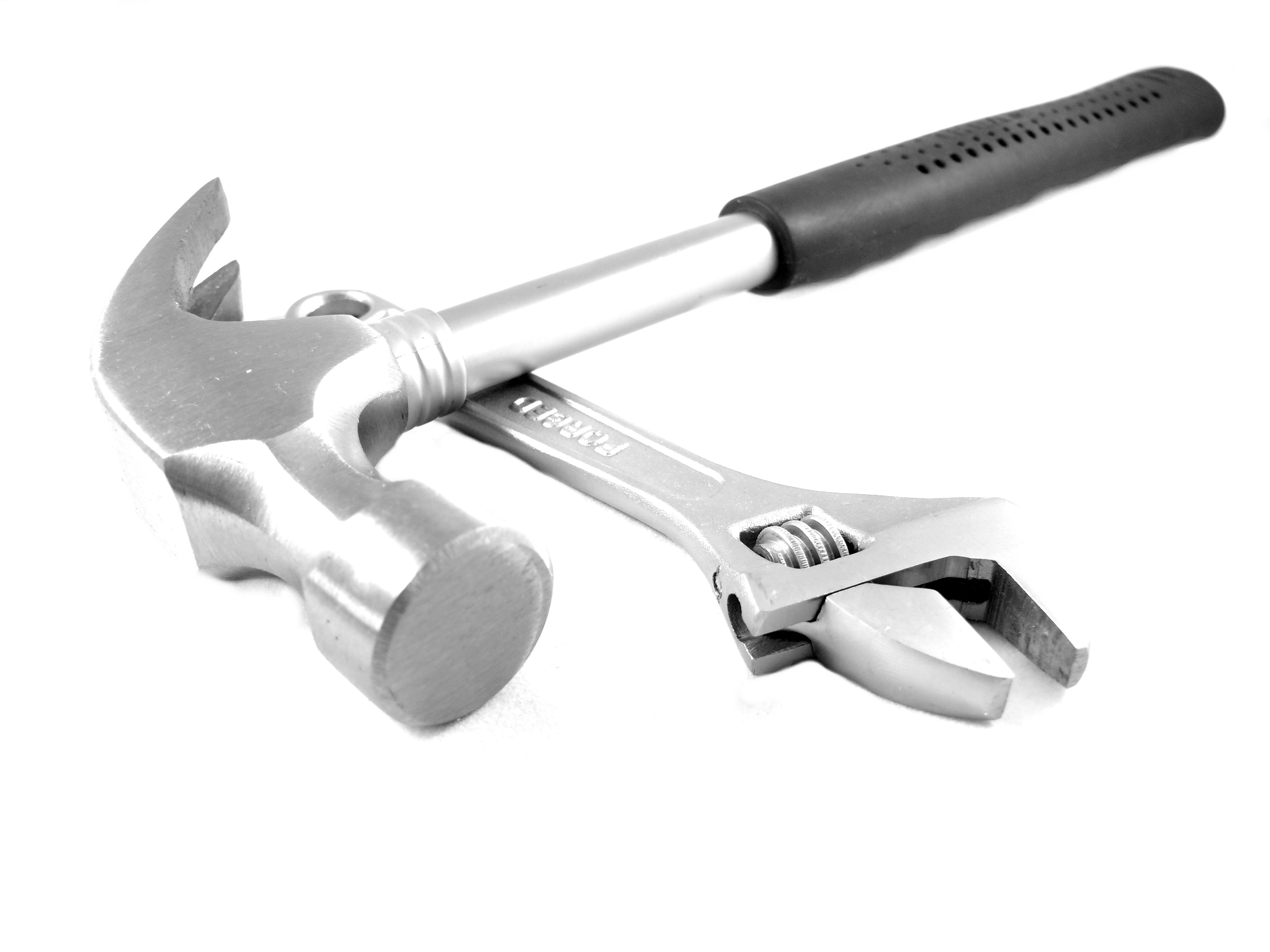 Shiny metal hammer with black handle and spanner, at white background ...