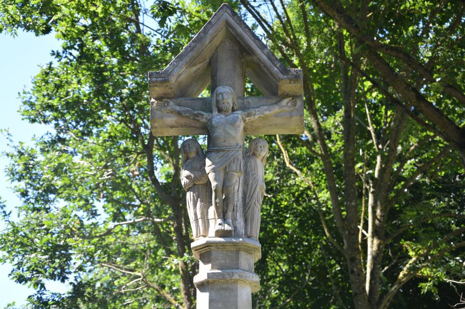 Beautiful statue with Jesus Christ on the cross, near the green trees ...