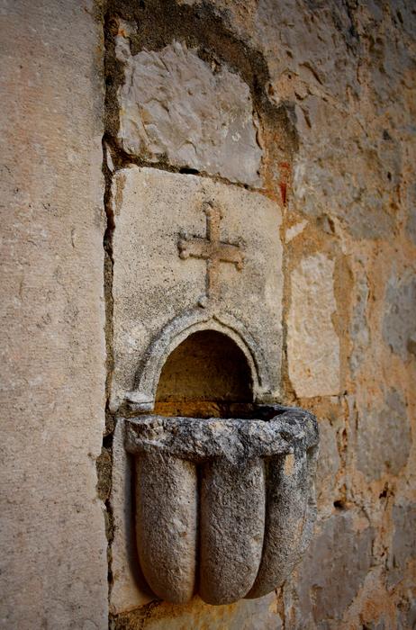 Cross, stone carving on wall above holy water fountain free image download