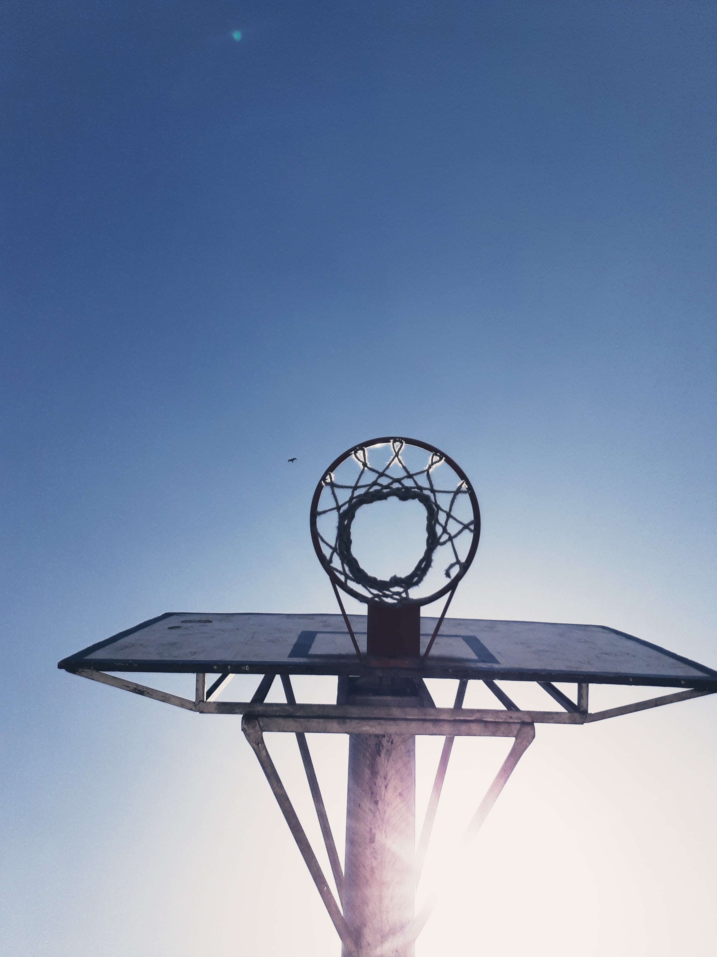 Low angle shot of the basketball net, in sunlight, under the blue sky ...