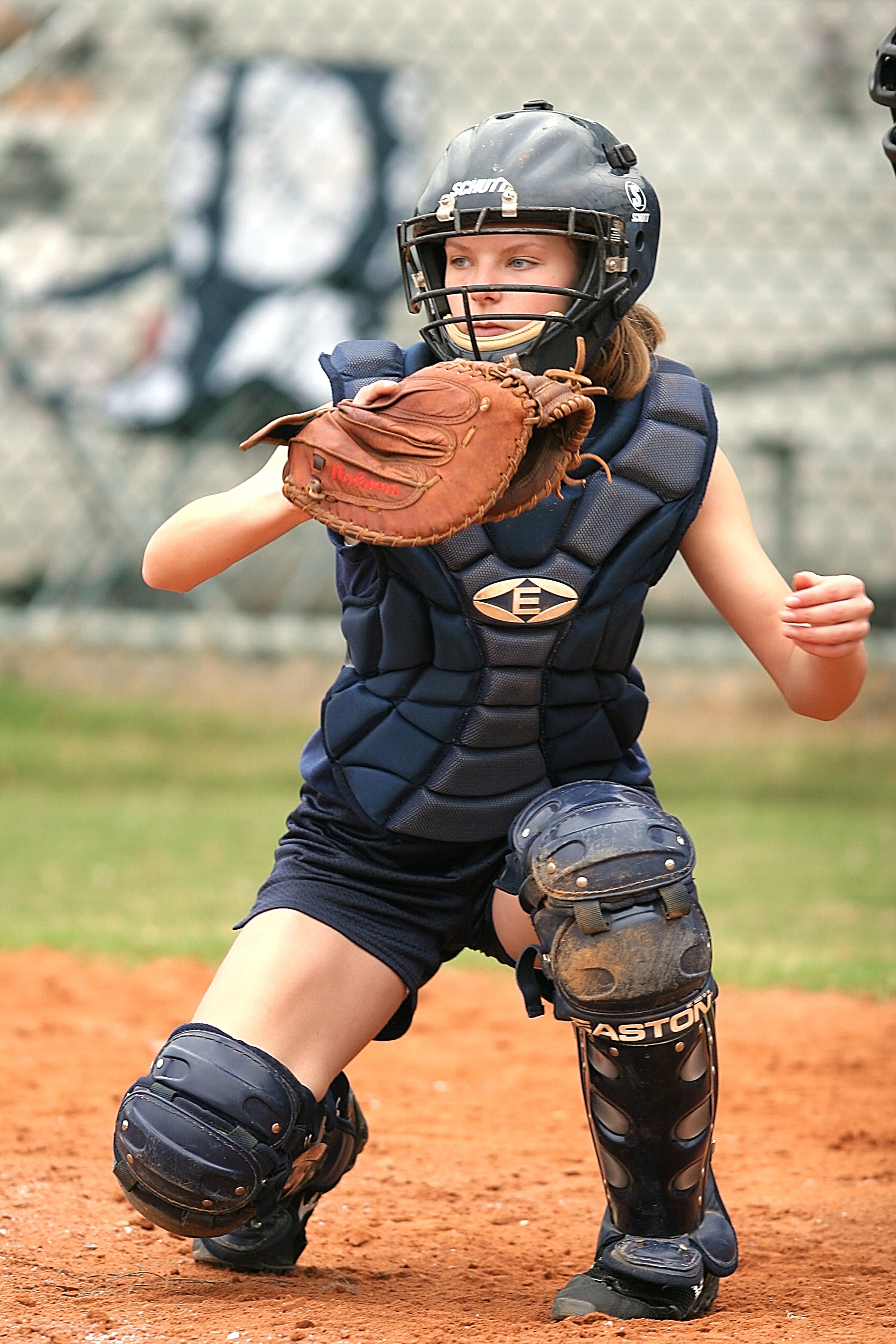 Softball catcher player on the field, with the fence, on the ...