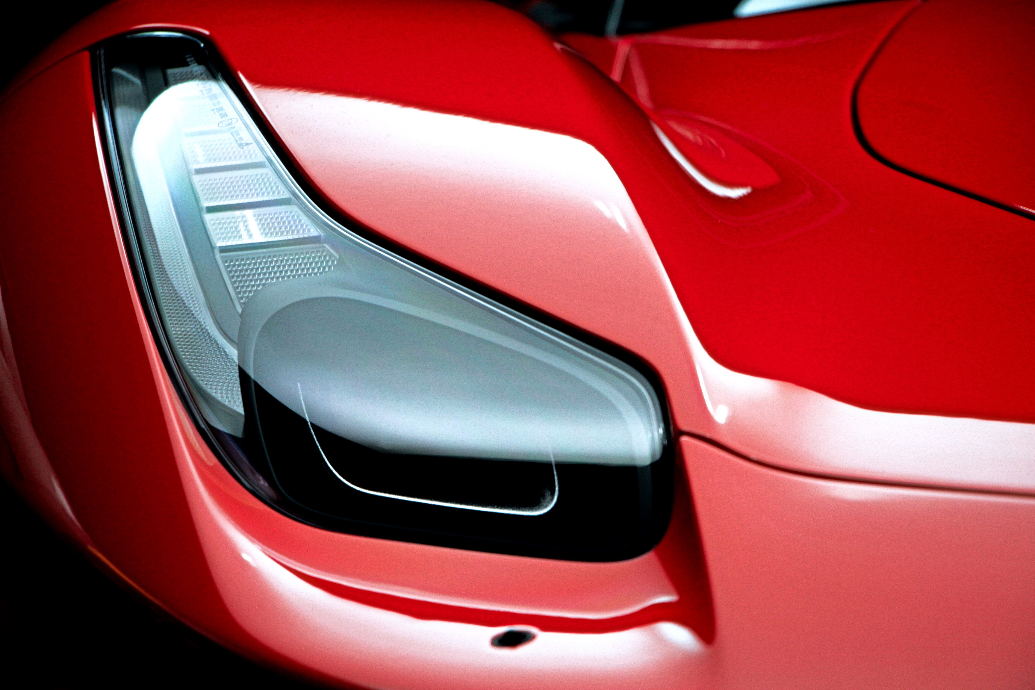 Close-up of the shiny, red Ferrari car with headlight free image download