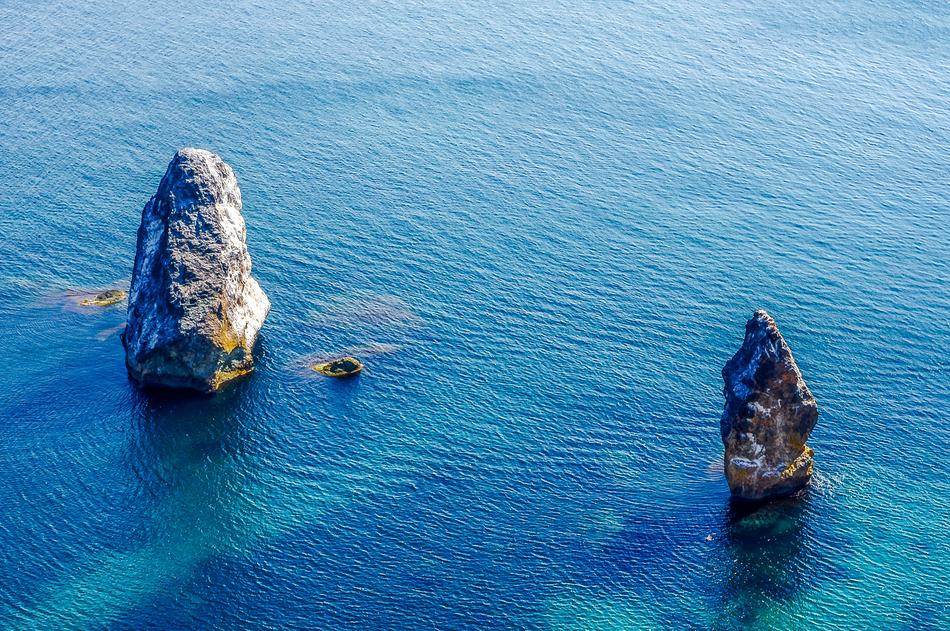 Beautiful and colorful rocks in the sea with ripple, in sunlight, near ...