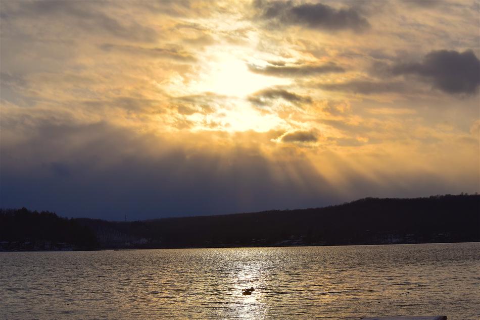 Scenic Sunset, sun beams bursting through clouds over calm Water free ...