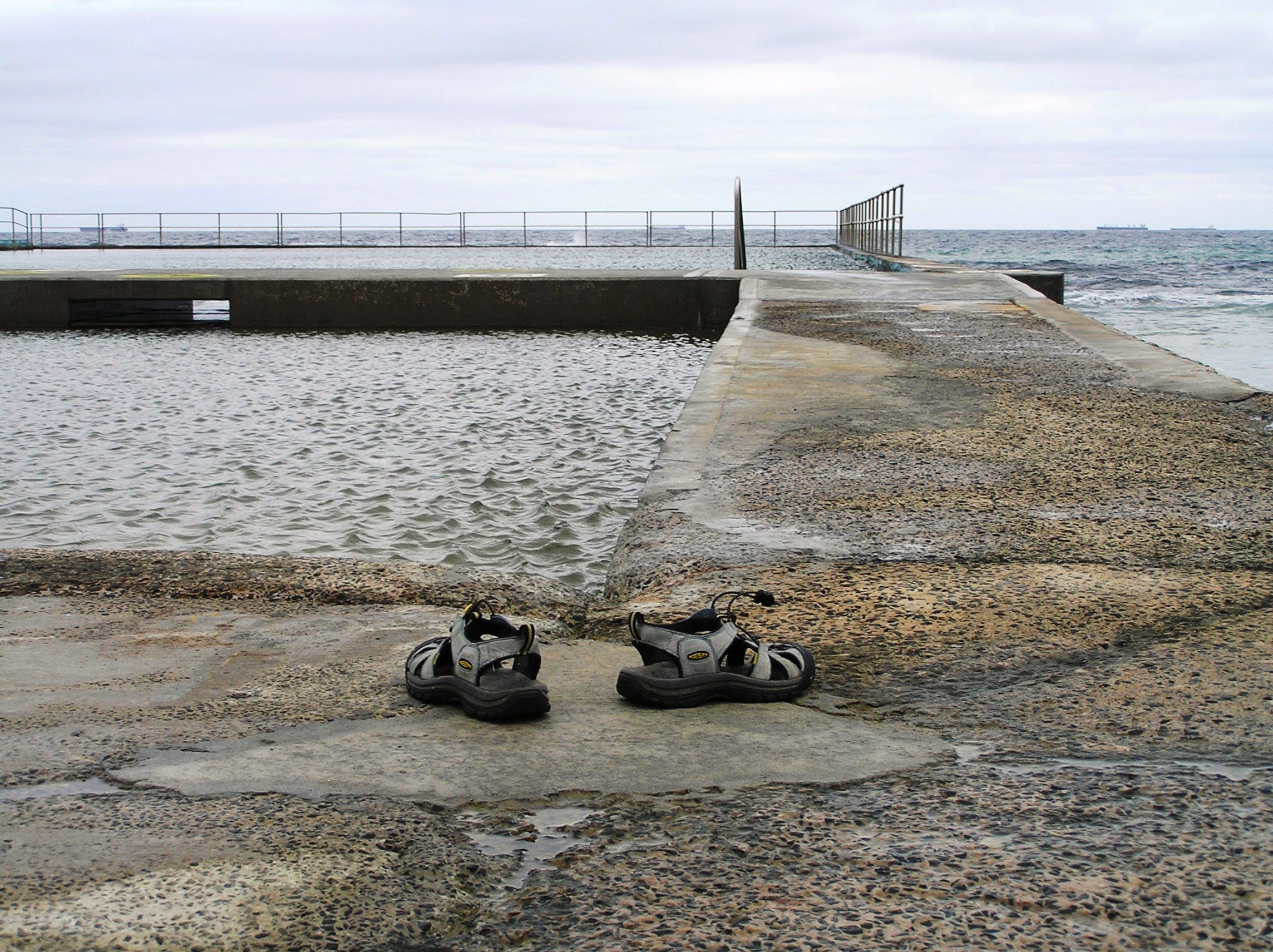 Shoes near the stone bridge by the sea free image download