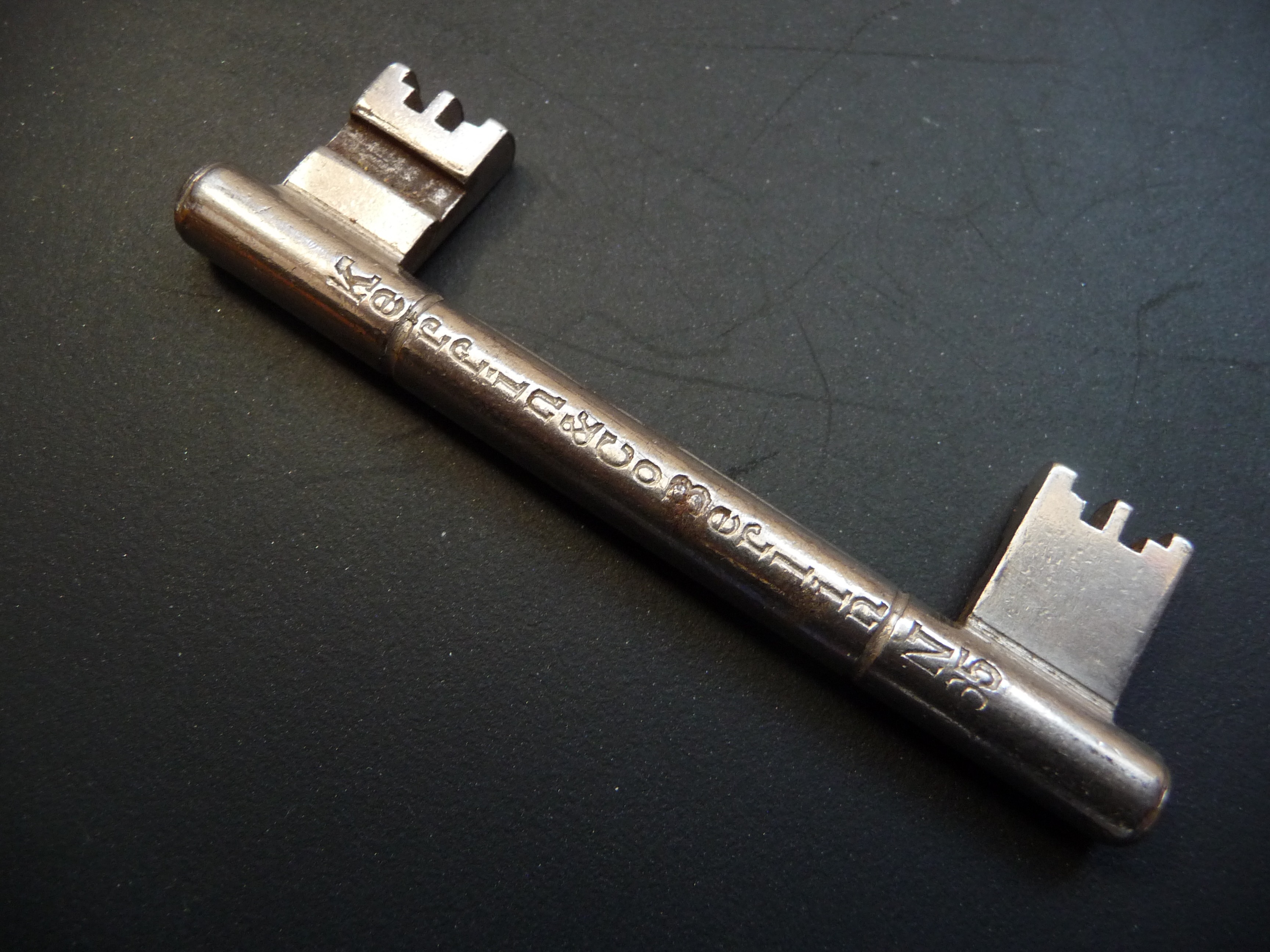 Close-up of the shiny, metal Berlin key with signs, on the black ...